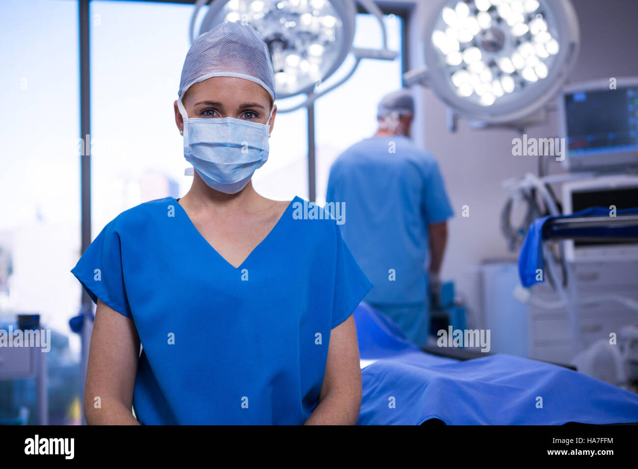 Portrait of female nurse wearing surgical mask in operation theater ...