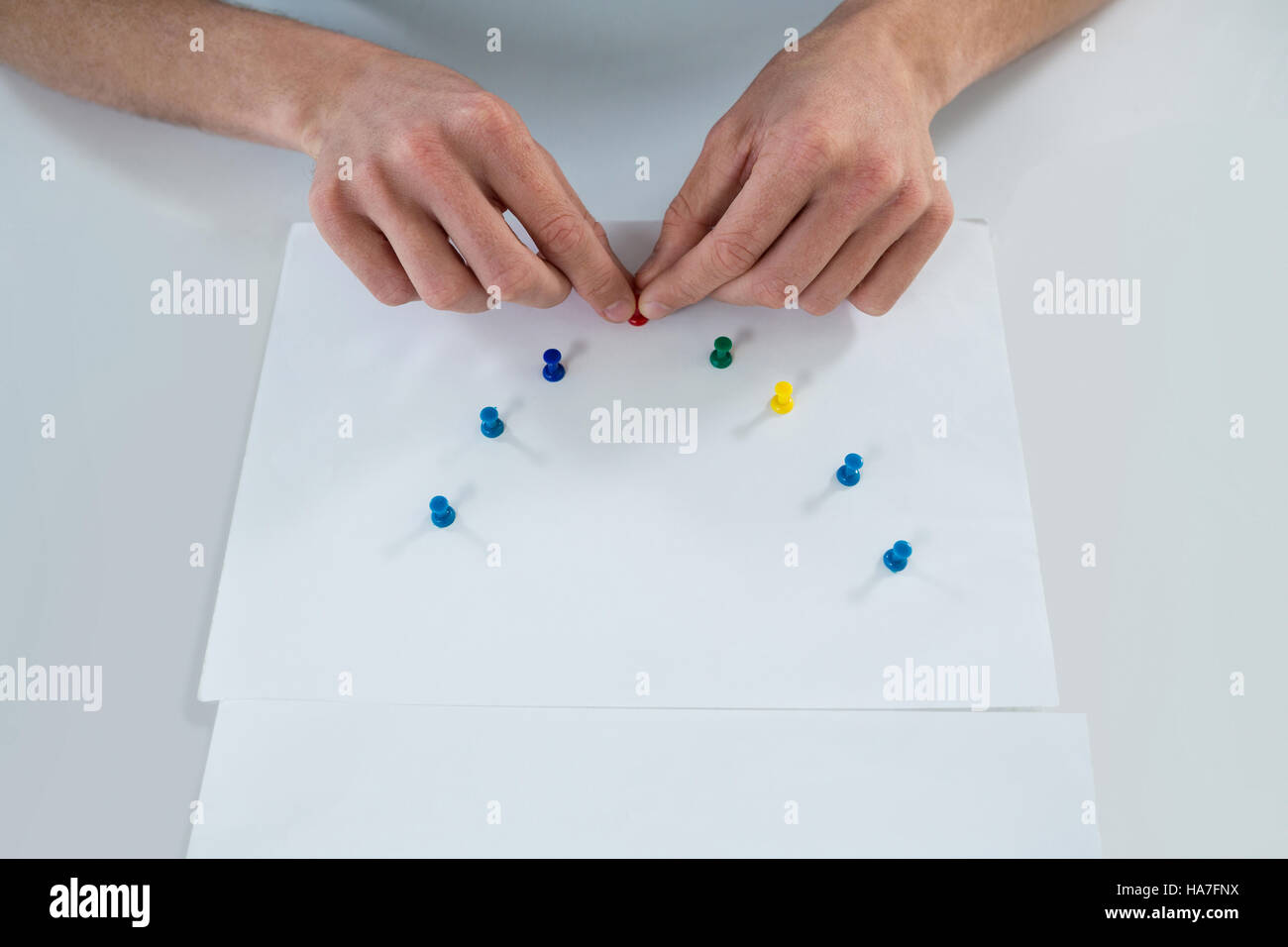 Man attaching push pin on paper Stock Photo - Alamy