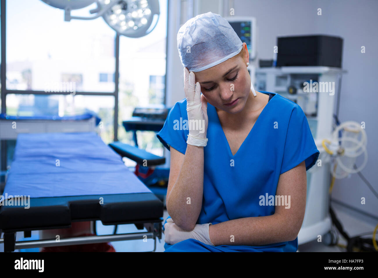 Sad female nurse sitting in operation theater Stock Photo - Alamy