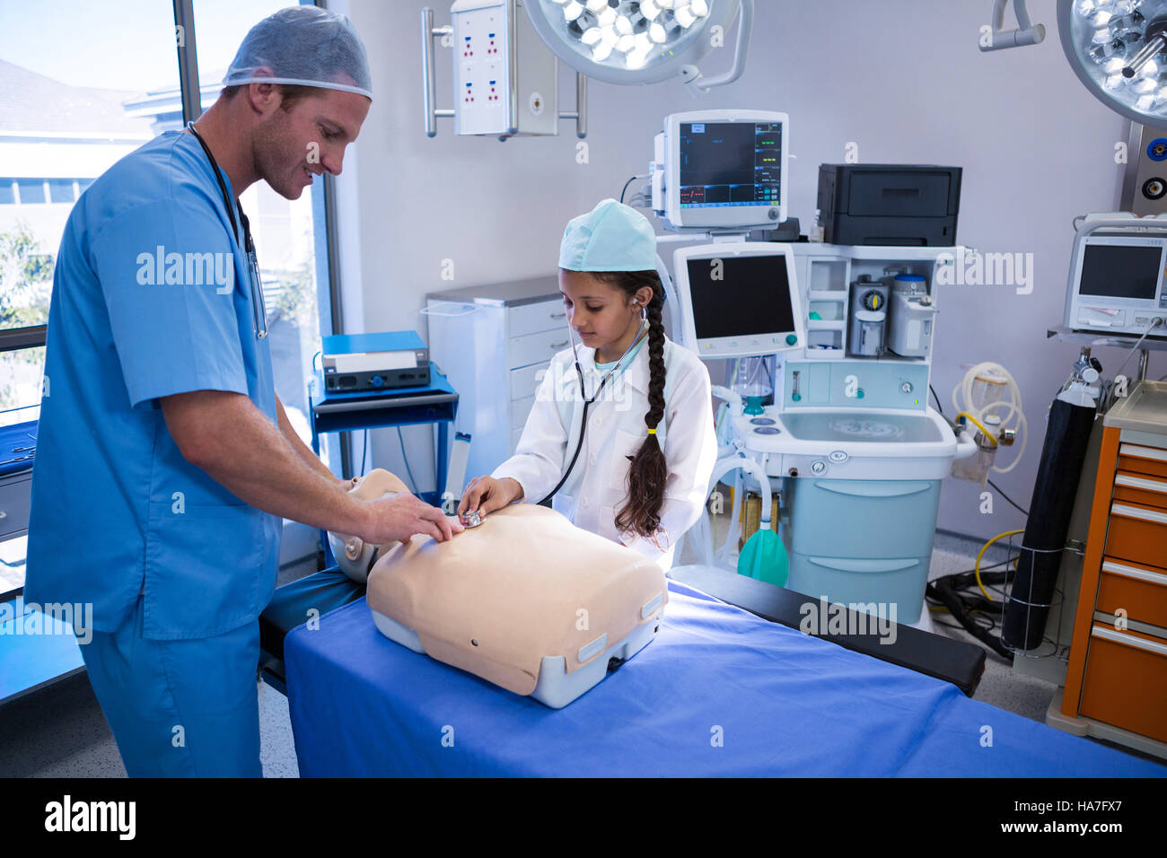 Doctor assisting girl in examining on dummy with stethoscope Stock ...