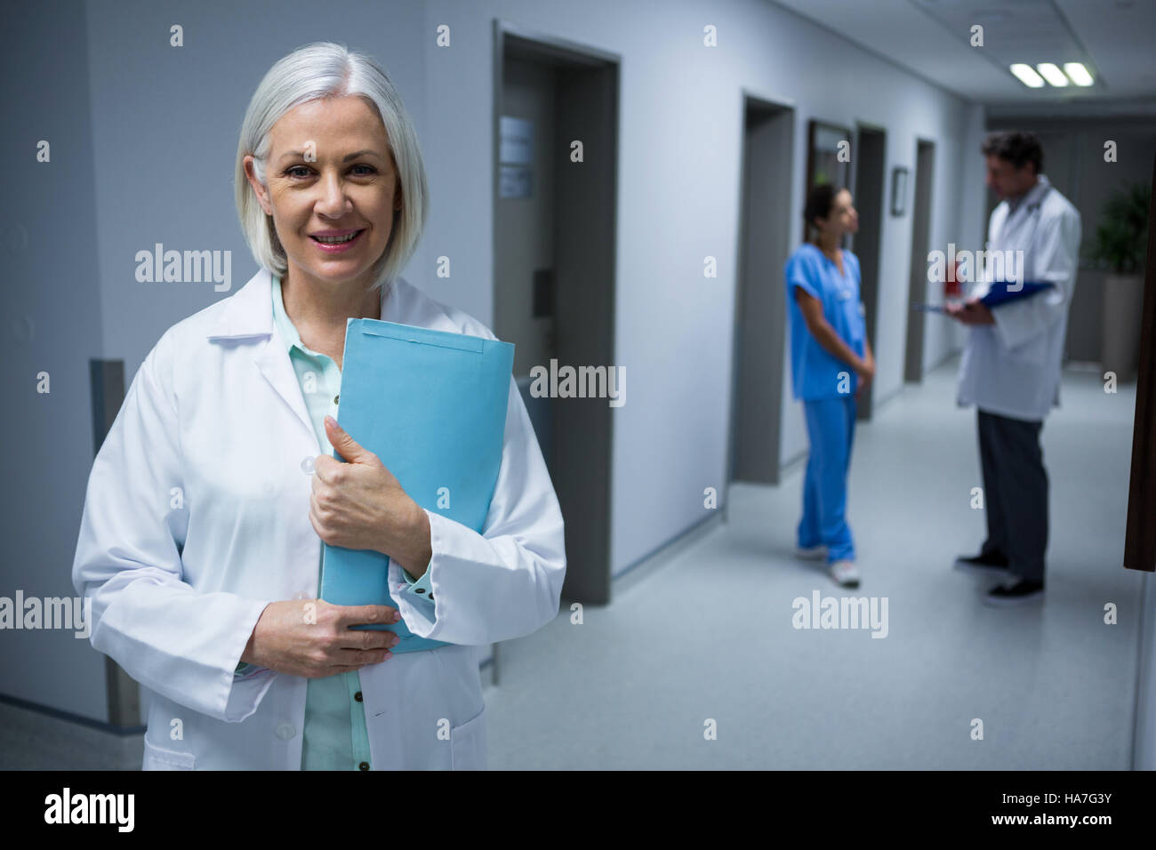Portrait of doctor holding file in corridor Stock Photo - Alamy