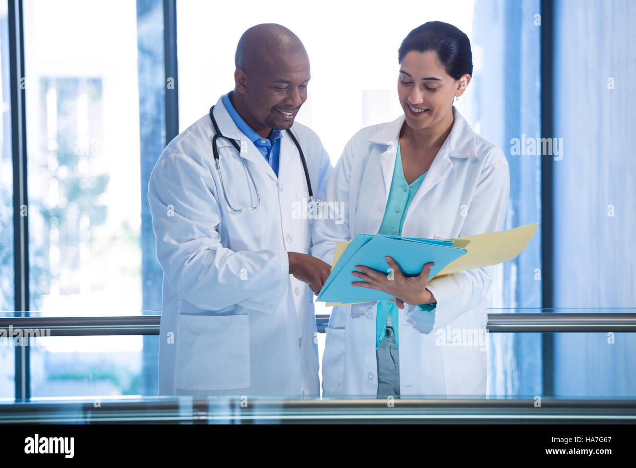 Male and female doctors having over file in corridor Stock Photo - Alamy