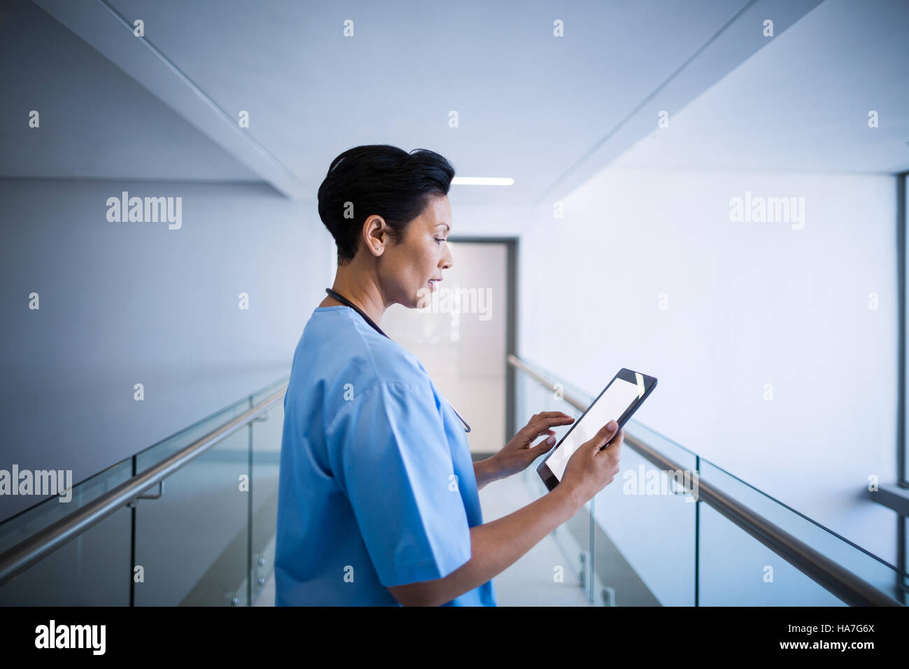 Female nurse using digital tablet in corridor Stock Photo - Alamy