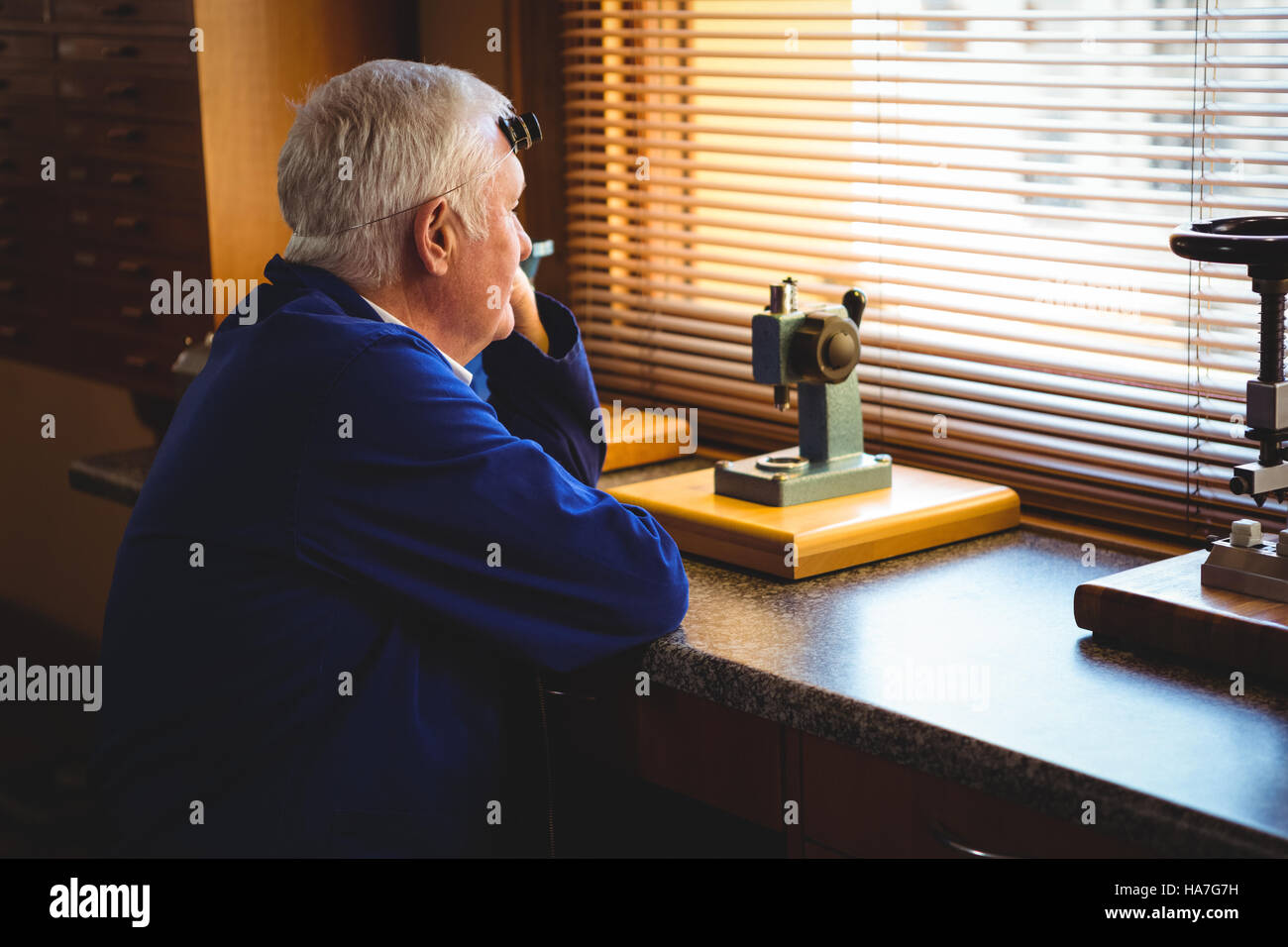 Thoughtful horologist looking through window Stock Photo - Alamy