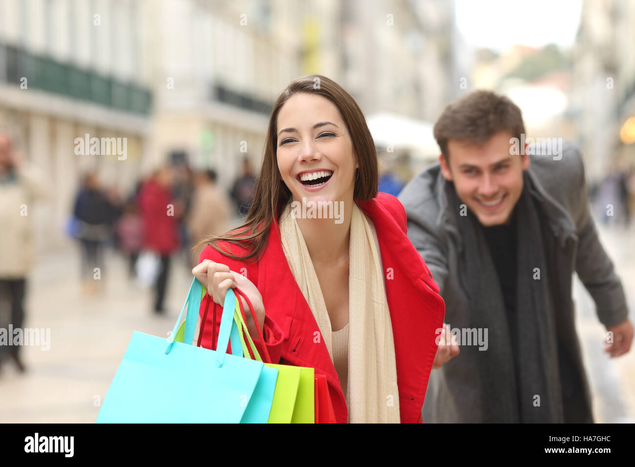 Front view of a casual couple of shoppers running in the street towards ...