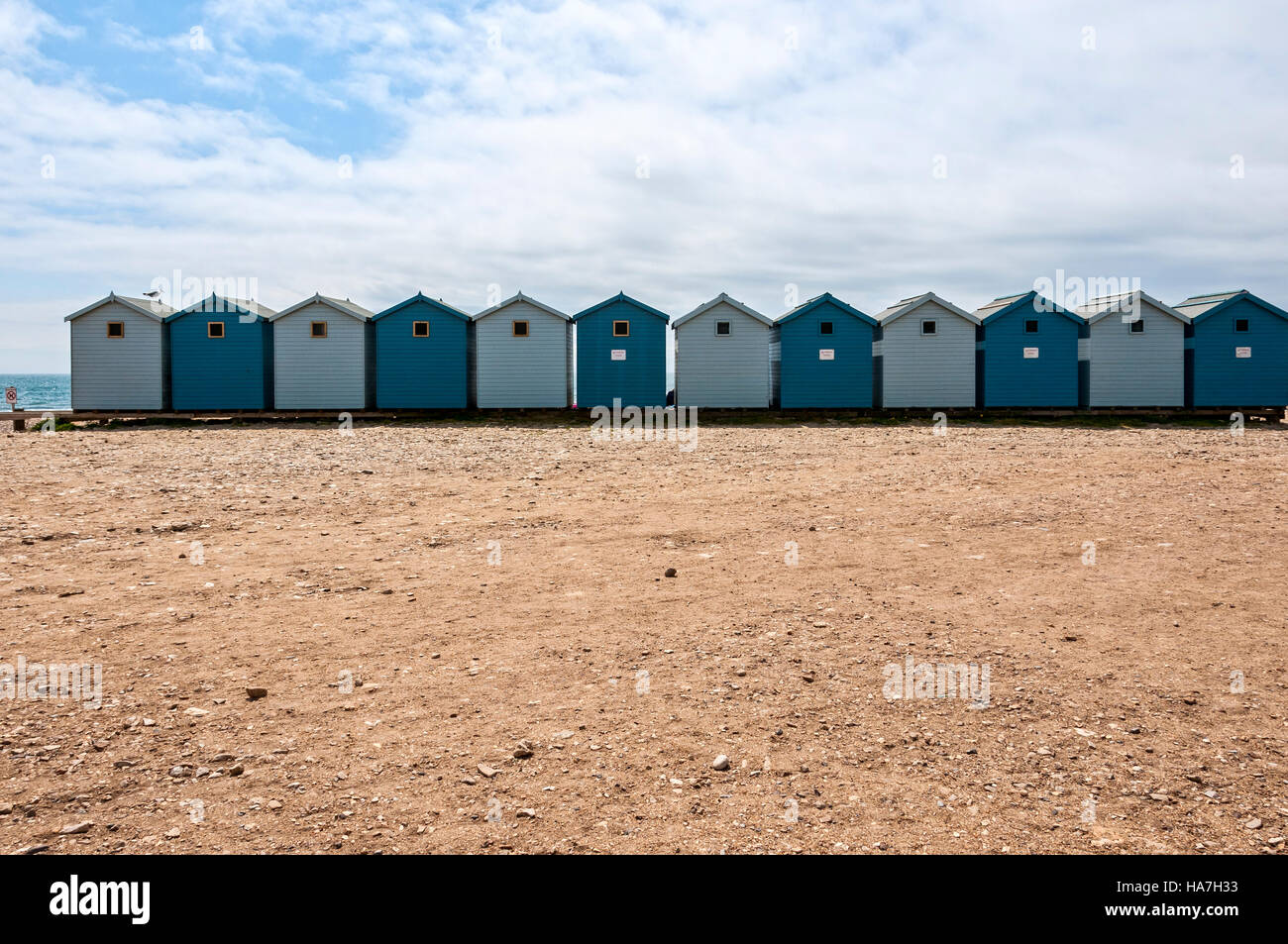 A row of beach huts sitting on the top edge of the beach are protected ...