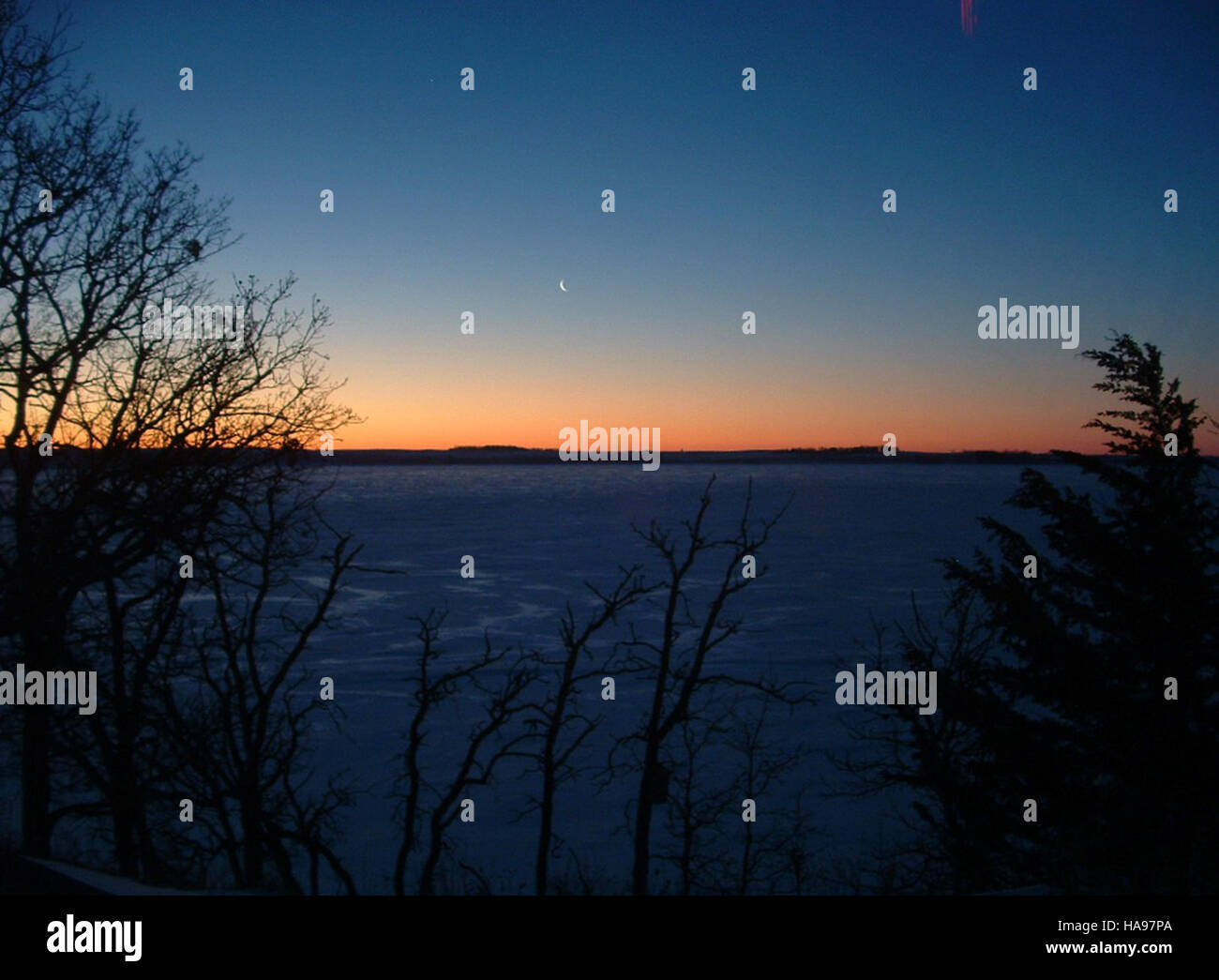 A scenic photograph of a sunrise with the moon still visible in the sky ...