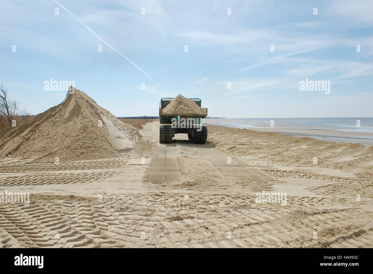 A rubber-tracked dump truck transports sand at Kimbles Beach, a ...