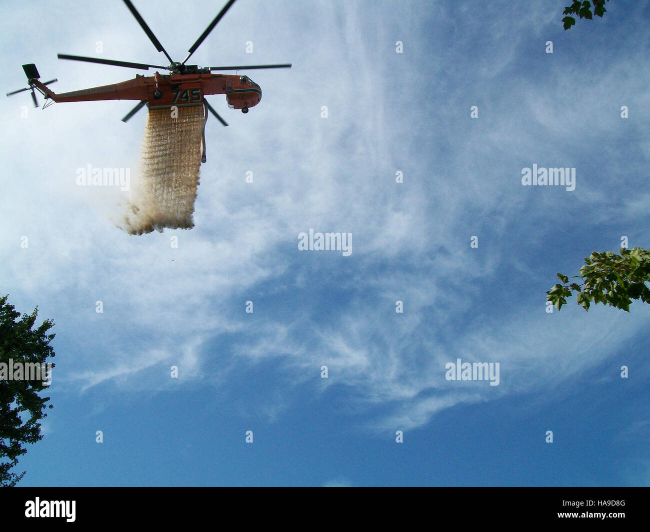 A Sikorsky Sky Crane helicopter performs a water drop to combat ...