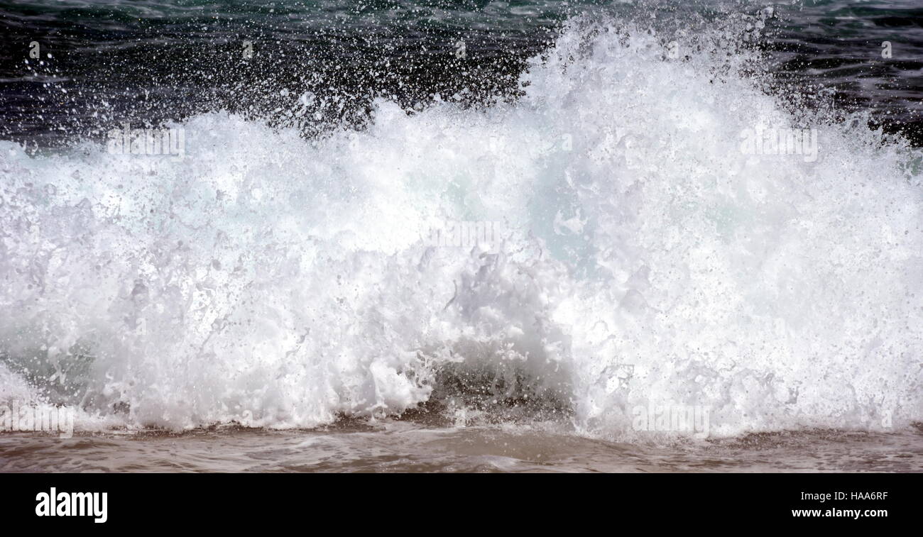 White spray splashing on the beach. Ocean tidal waves breaking on a ...