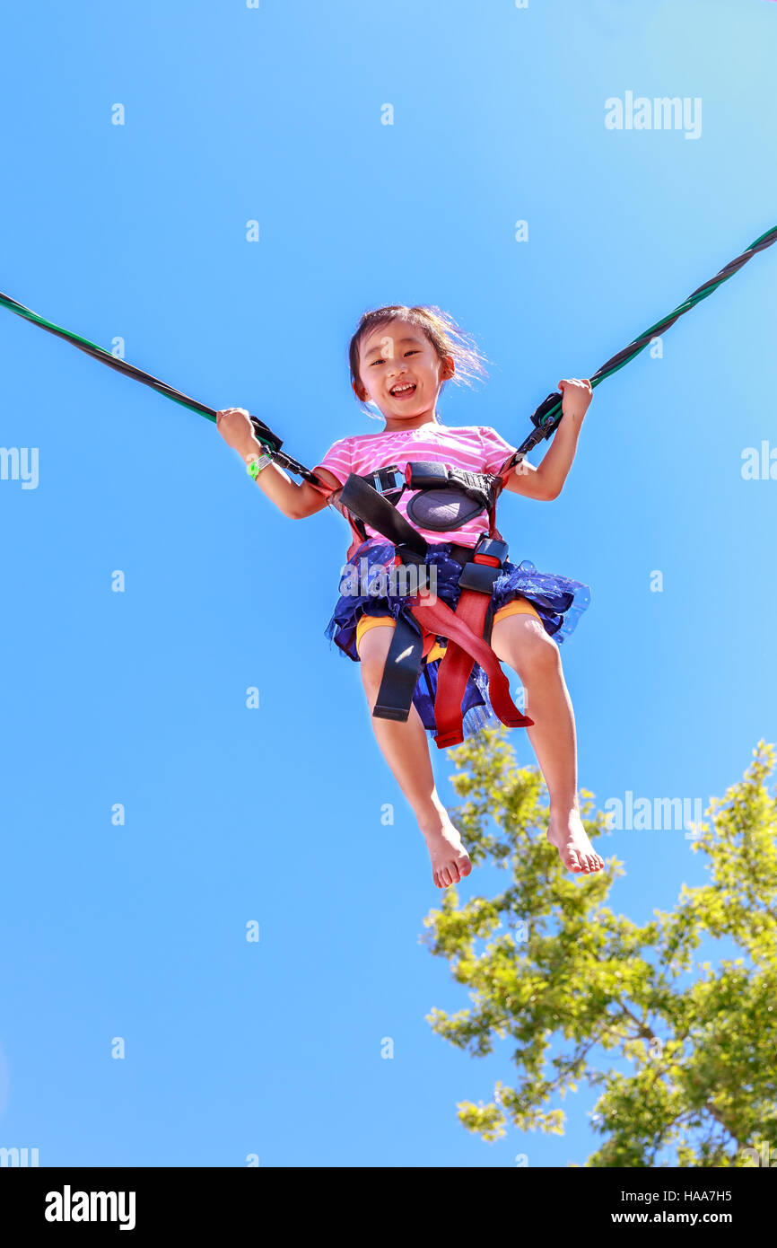 Little girl having a good time bungee jumping in county fair Stock ...