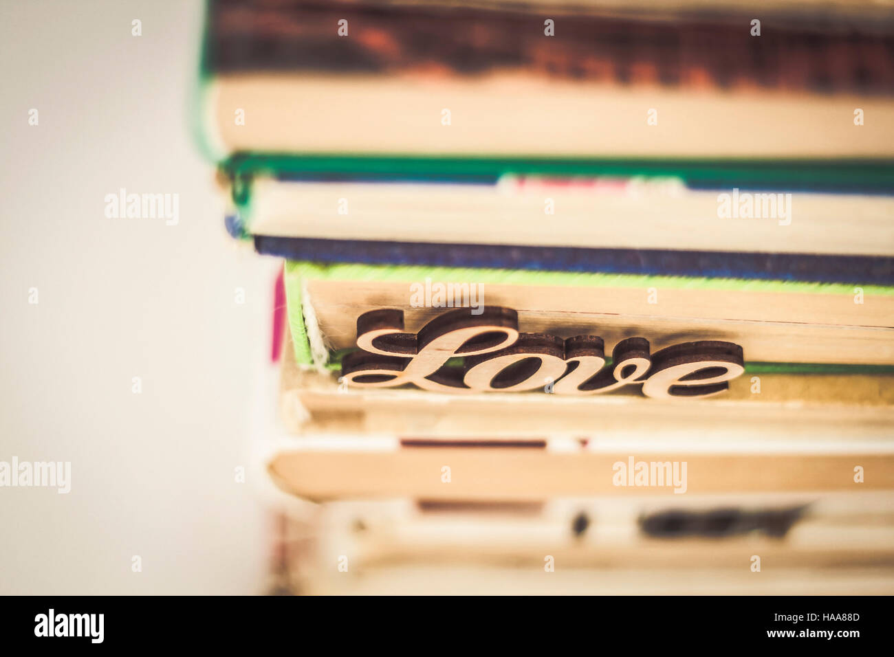 on a stack of old books wooden word love Stock Photo - Alamy