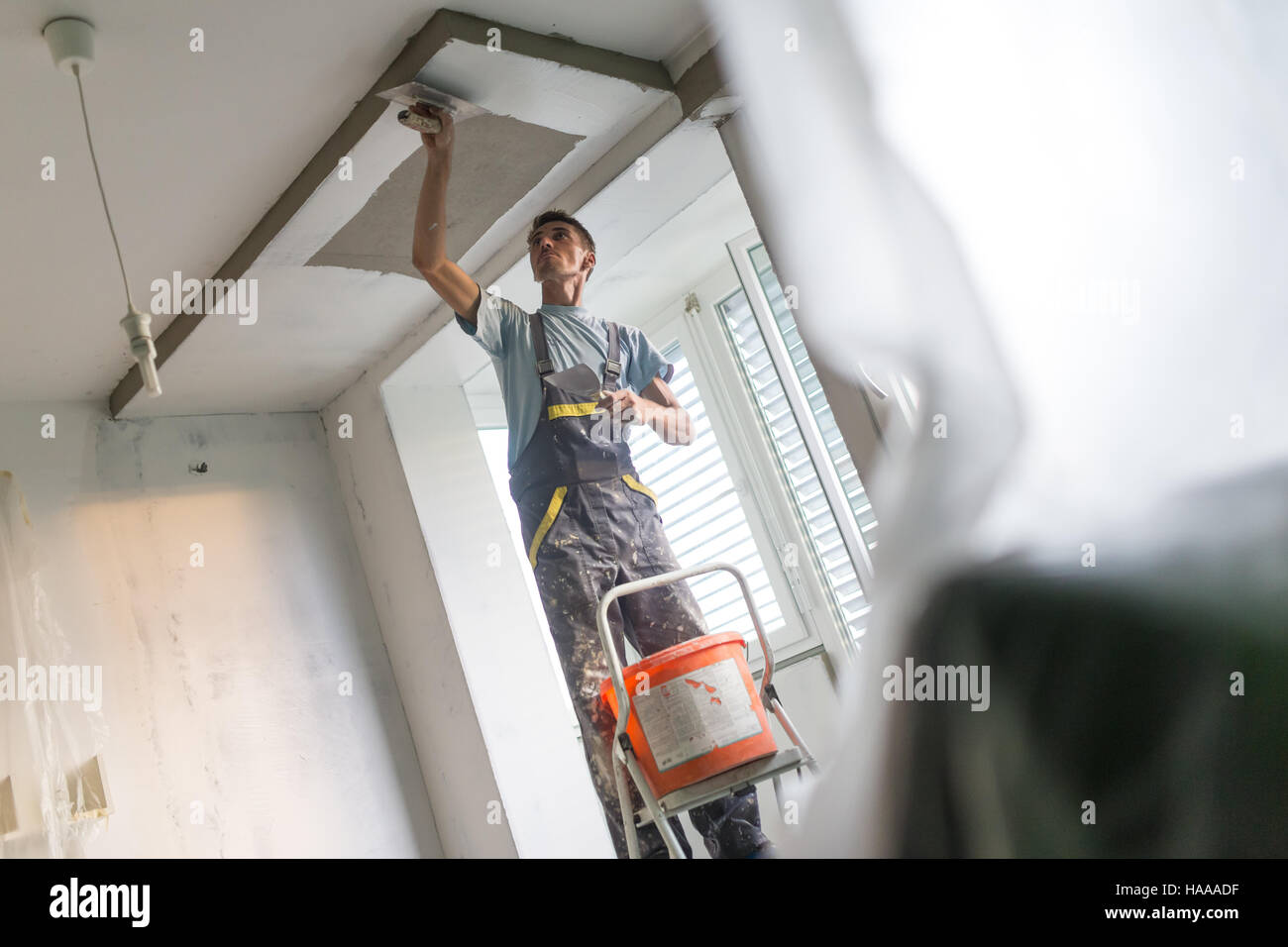 Plasterer renovating indoor walls and ceilings. Construction finishing ...