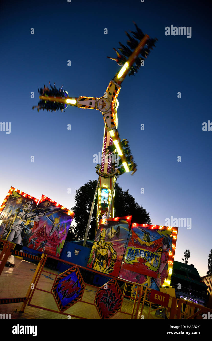 nightime fairground thrill ride carrying passengers upside down high ...