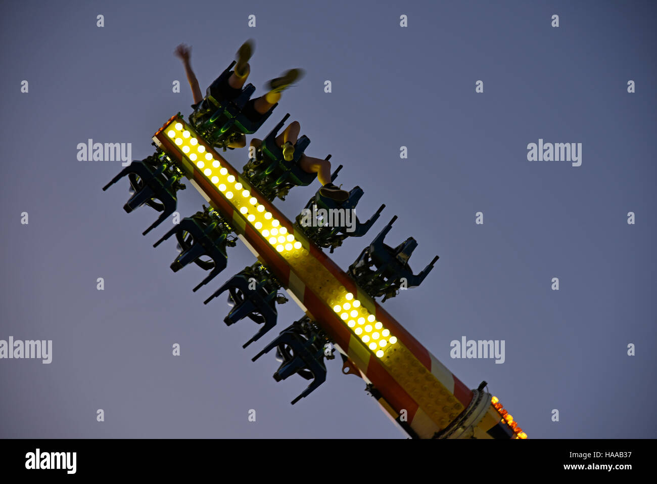 nightime fairground thrill ride carrying passengers upside down high ...