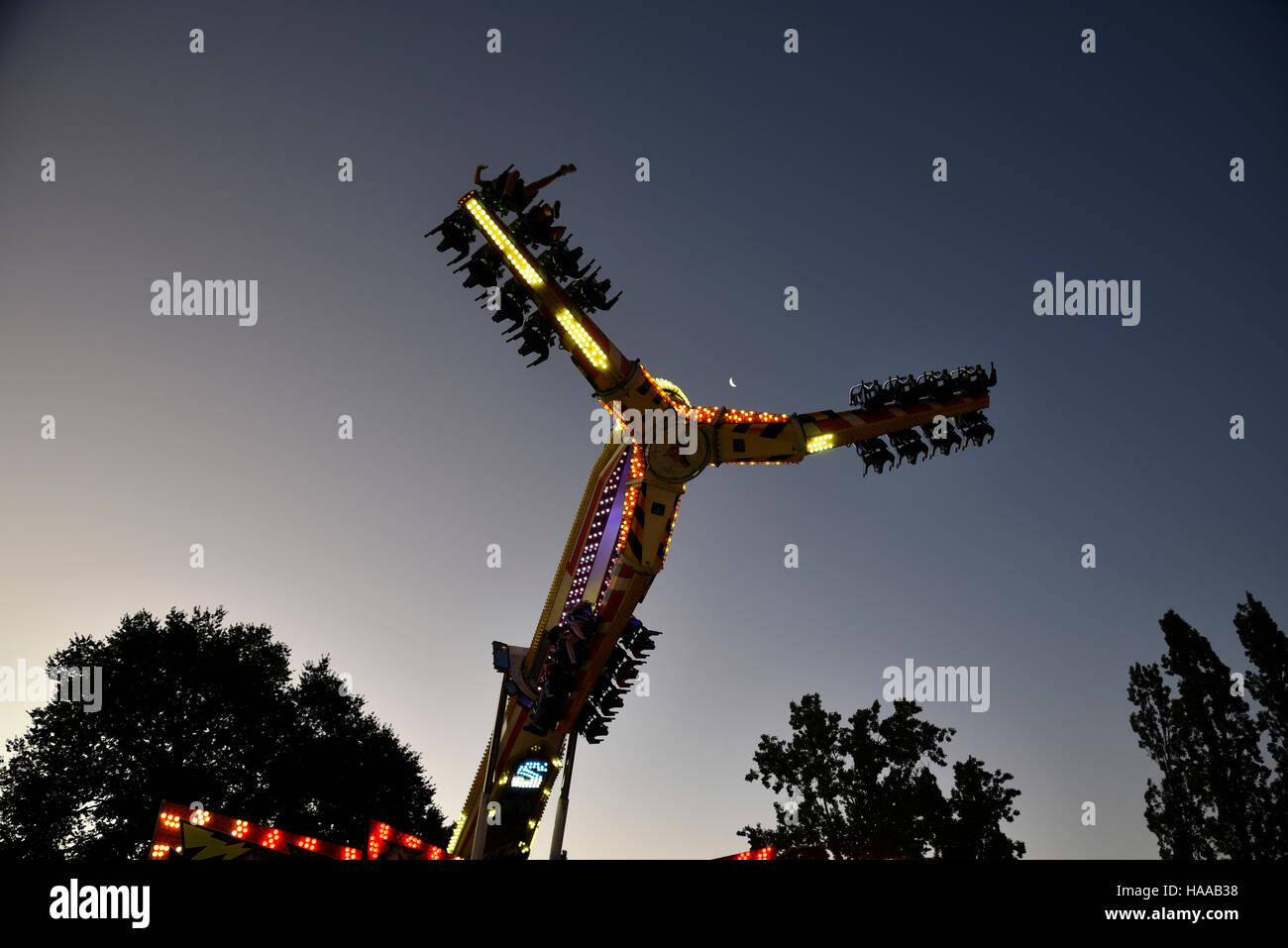 nightime fairground thrill ride carrying passengers upside down high ...