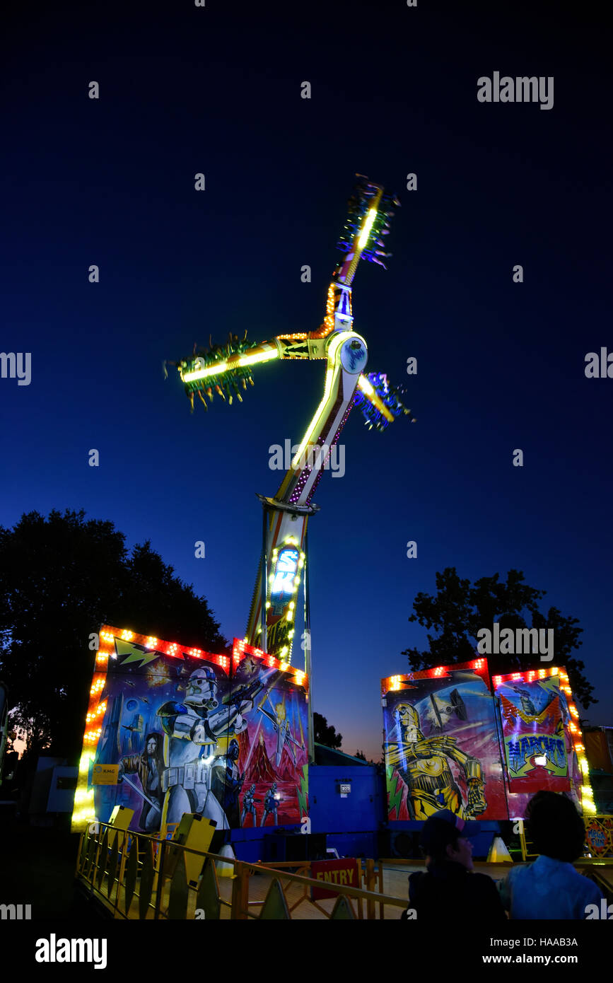nightime fairground thrill ride carrying passengers upside down high ...