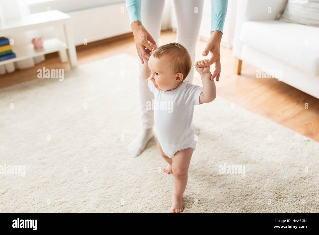 happy baby learning to walk with mother help Stock Photo - Alamy