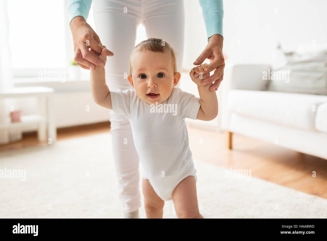 happy baby learning to walk with mother help Stock Photo - Alamy