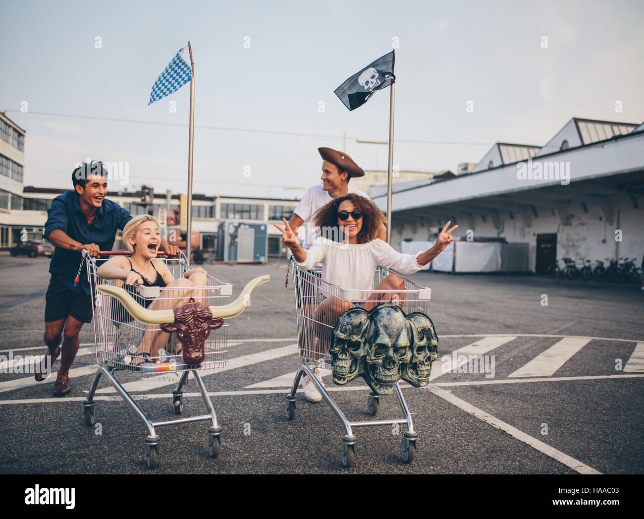 Multiethnic young people racing with shopping cart. Young friends ...