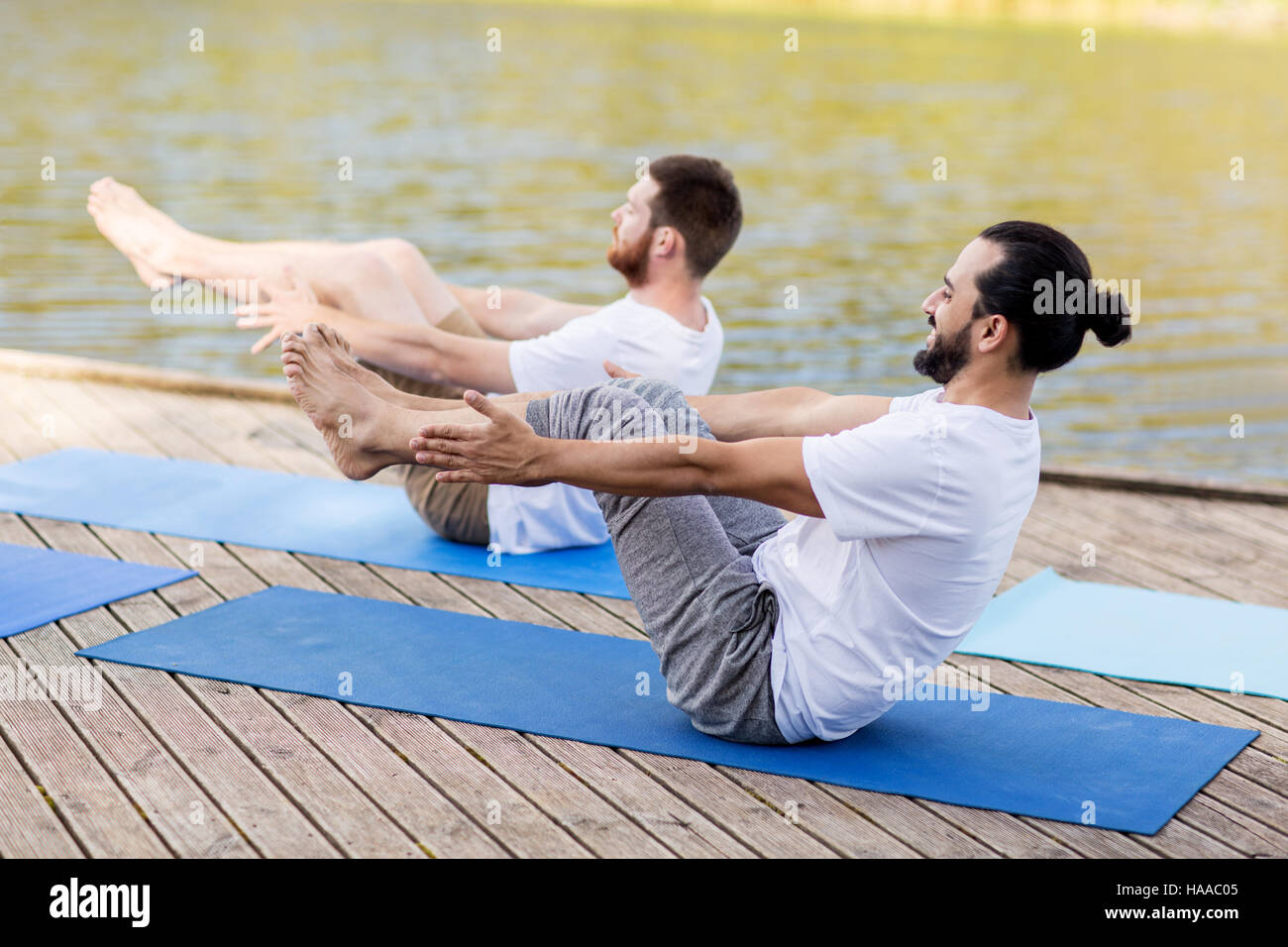 men making yoga in half-boat pose outdoors Stock Photo - Alamy
