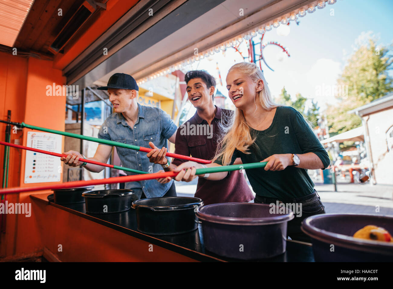 Group of friends having fun with fishing game in amusement park. Young ...