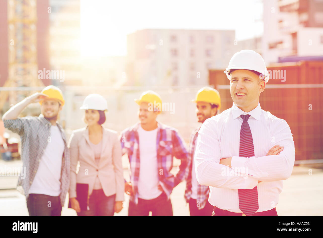group of smiling builders in hardhats outdoors Stock Photo - Alamy