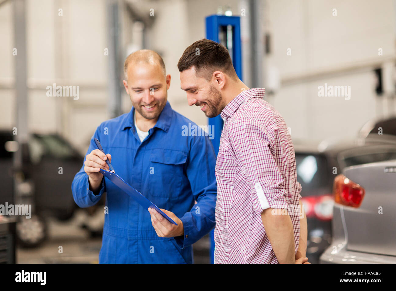auto mechanic with clipboard and man at car shop Stock Photo - Alamy