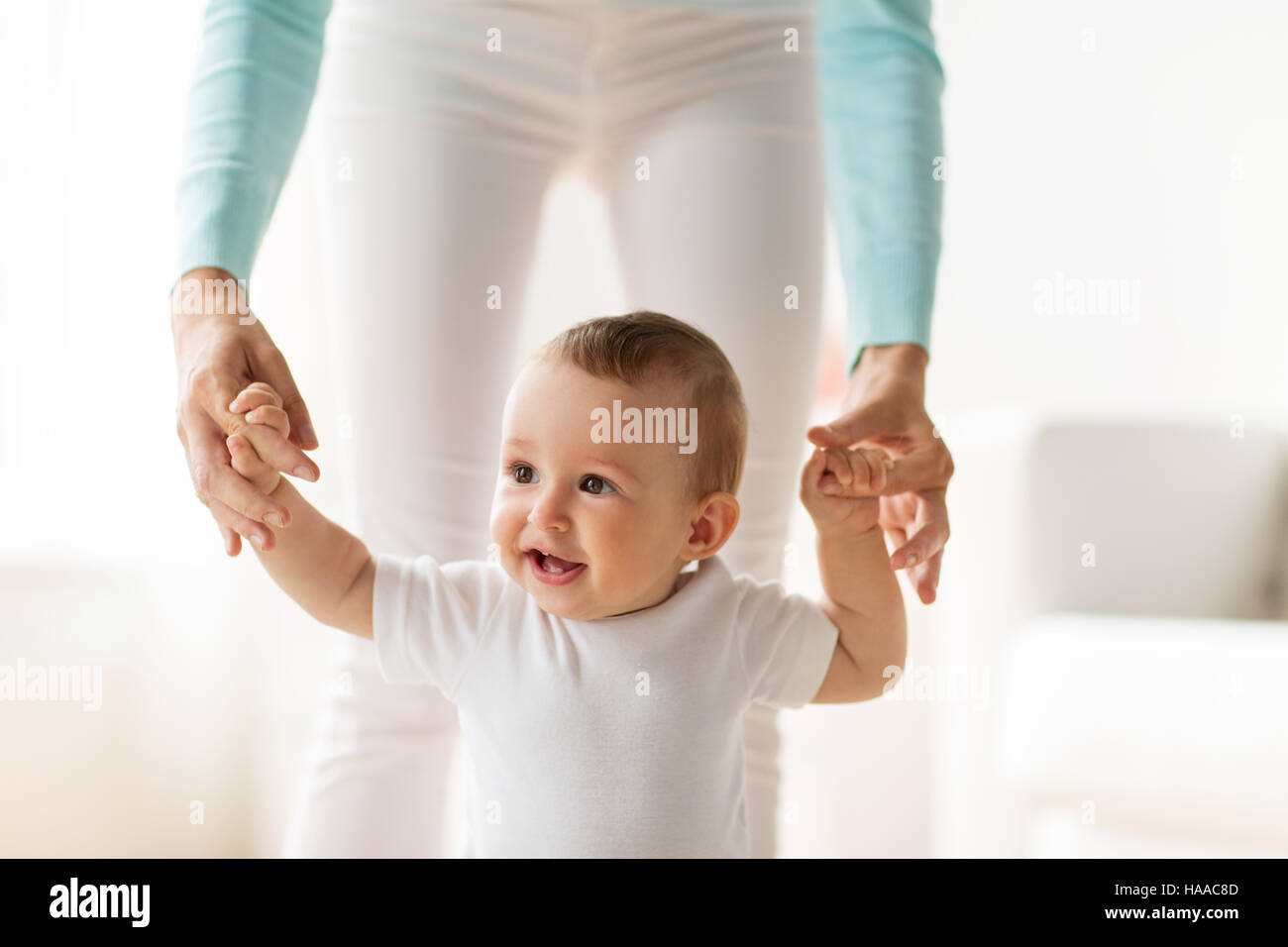 happy baby learning to walk with mother help Stock Photo - Alamy