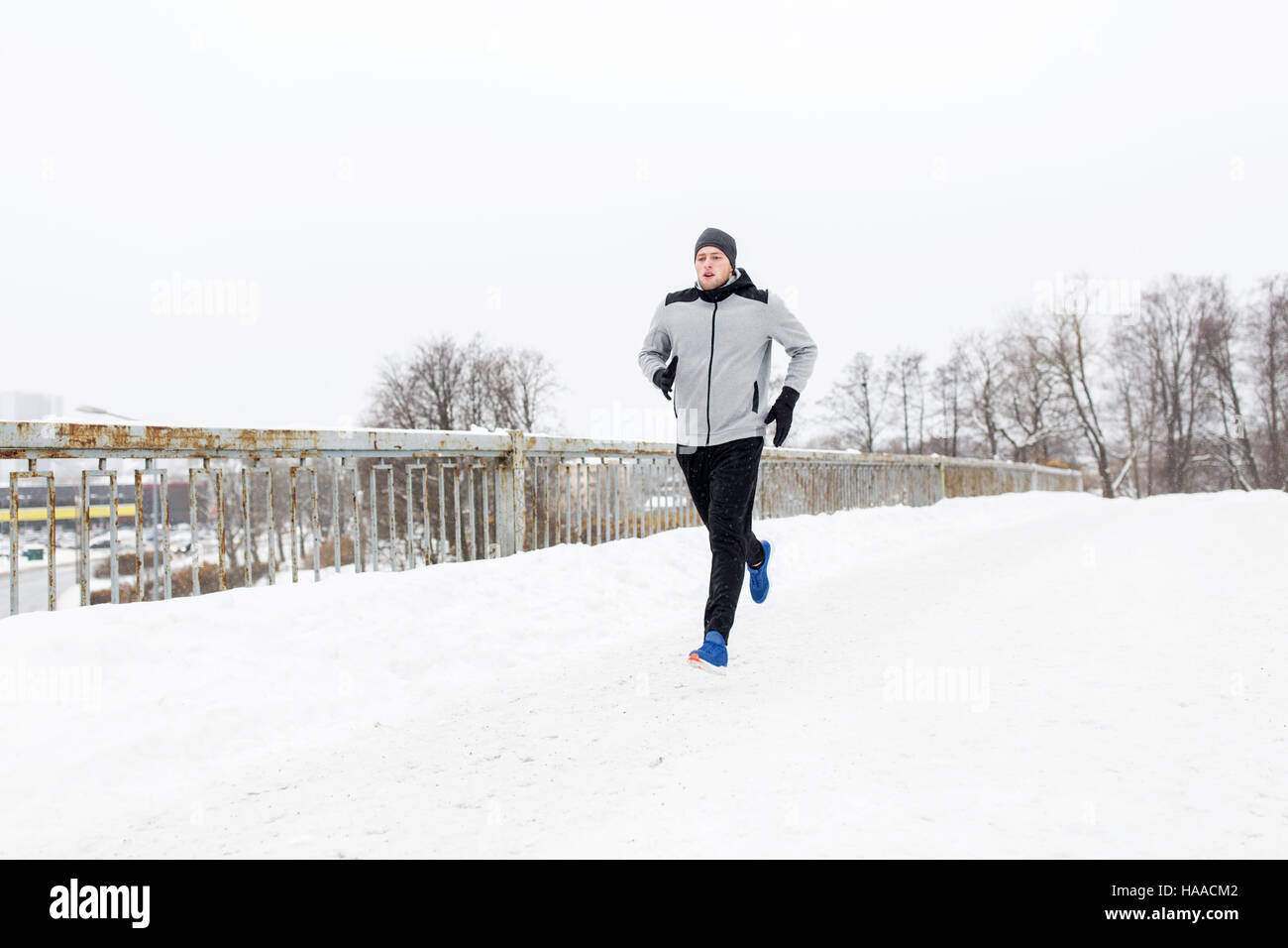 man running along snow covered winter bridge road Stock Photo - Alamy