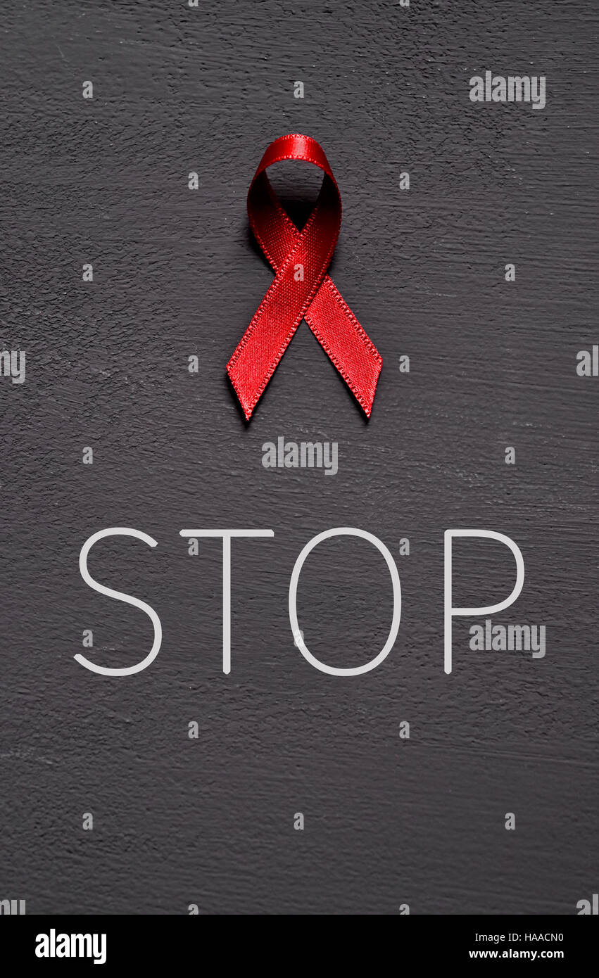 a red ribbon for the fight against AIDS and the word stop on a dark ...