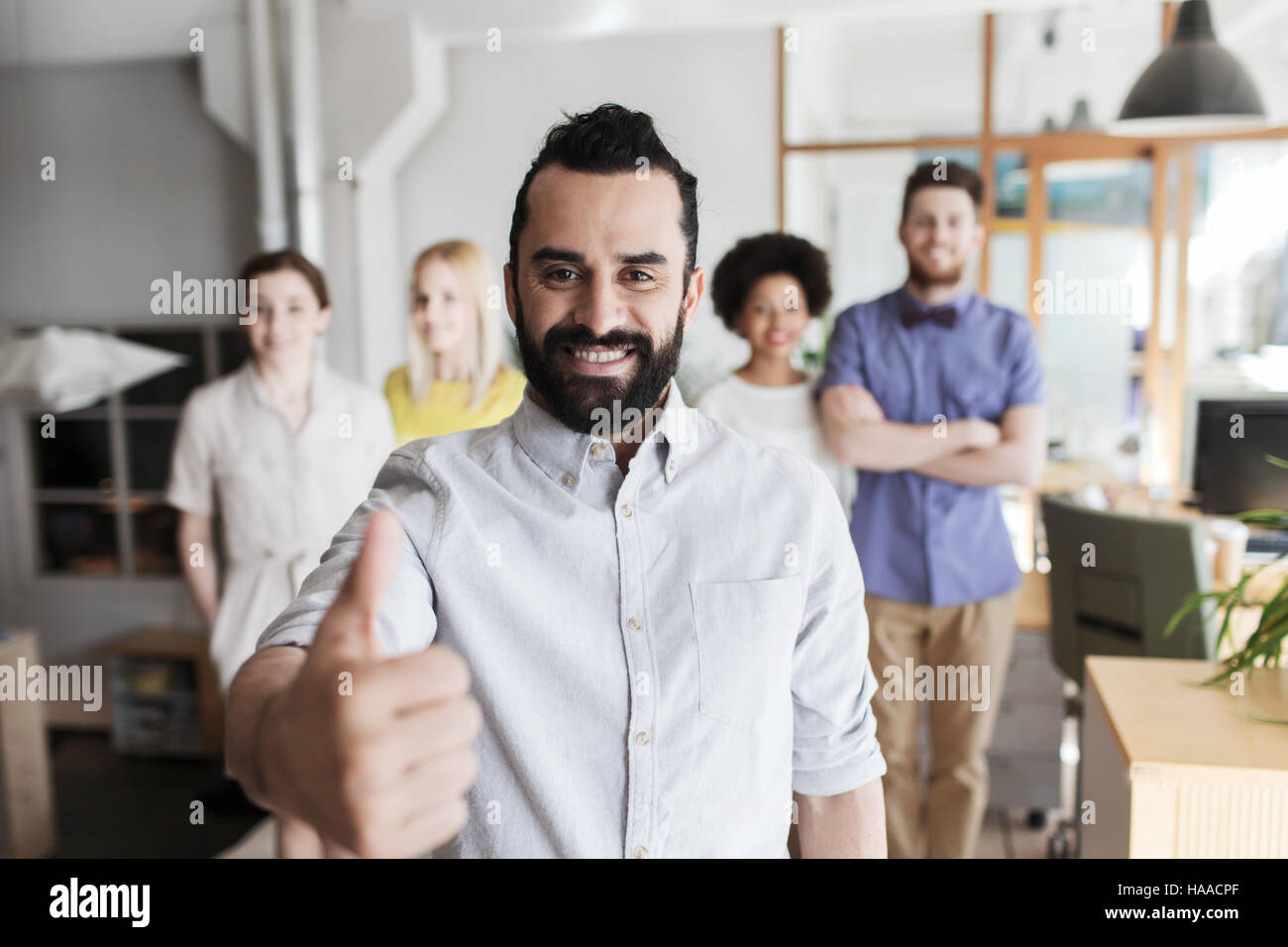 happy creative team showing thumbs up in office Stock Photo - Alamy