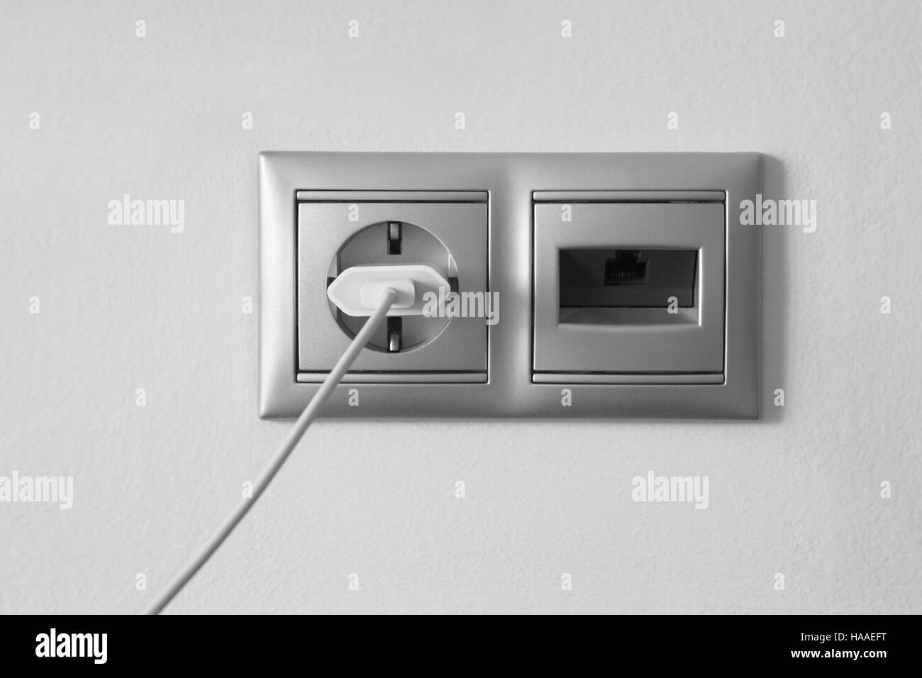 Electrical and ethernet socket on a textured white wall. Horizontal ...