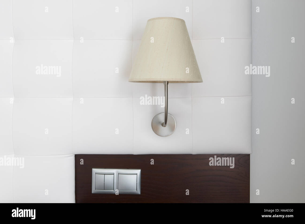 Hotel room interior detail with lamp, switches and white wall ...