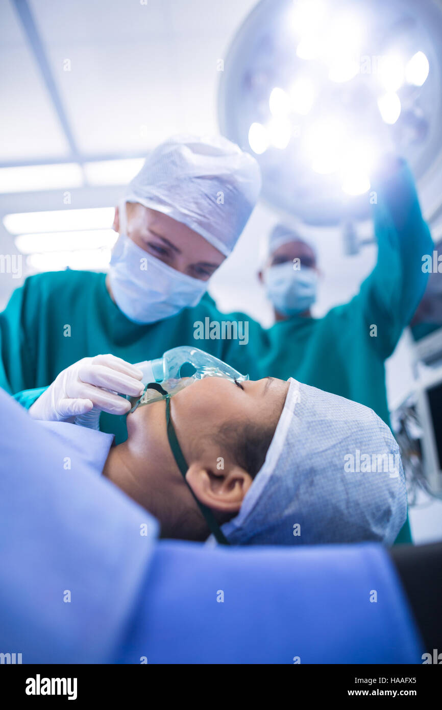 Surgeon adjusting oxygen mask on patient mouth in operation theater ...