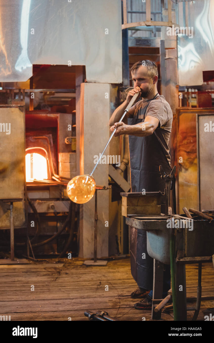 Glassblower shaping a glass on the blowpipe Stock Photo - Alamy
