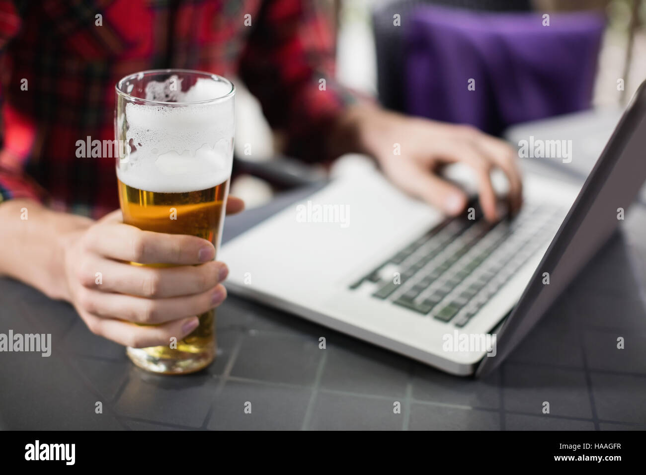 Man using laptop with glass of beer on table Stock Photo - Alamy