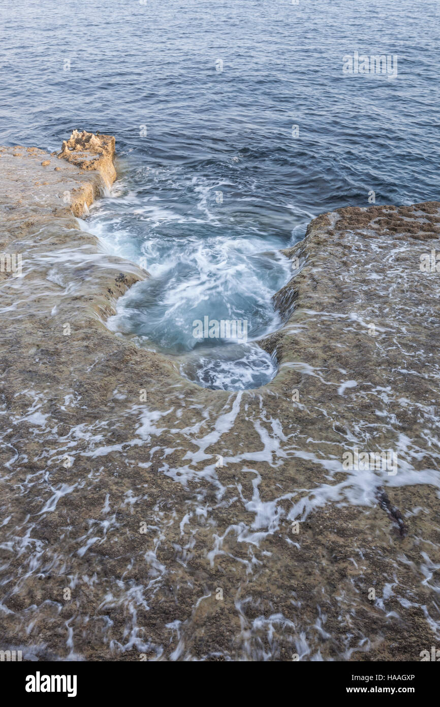 Waves breaking over a stone ledge Stock Photo - Alamy