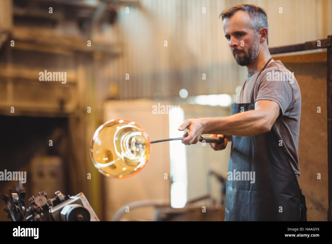 Glassblower shaping a glass on the blowpipe Stock Photo - Alamy