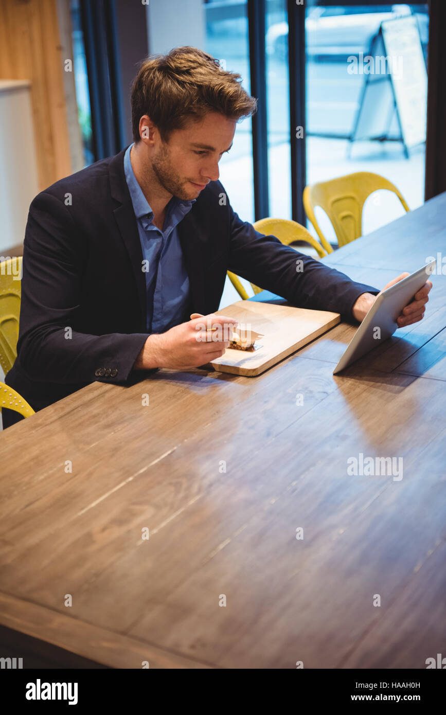 Businessman using digital tablet while having snacks Stock Photo - Alamy