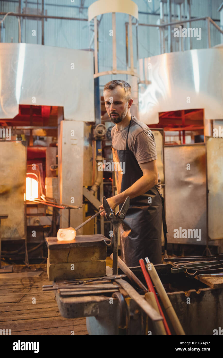 Glassblower shaping a molten glass on marver table Stock Photo - Alamy