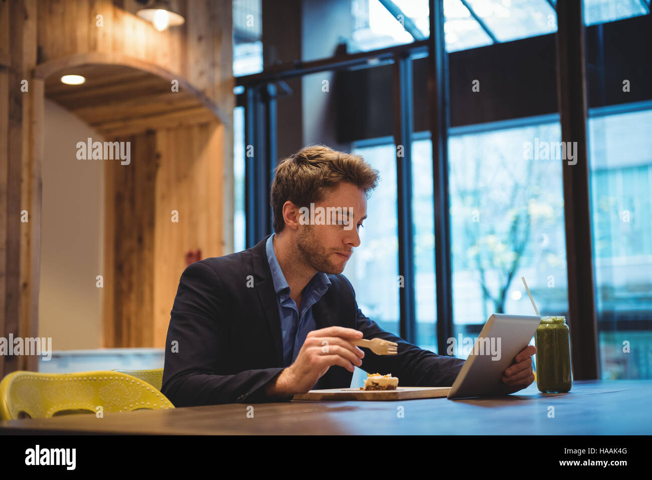 Businessman using digital tablet while having snacks Stock Photo - Alamy