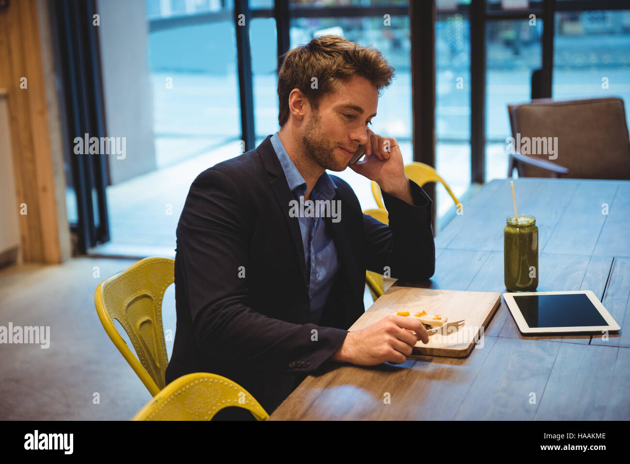 Businessman talking on mobile phone while having snacks Stock Photo - Alamy