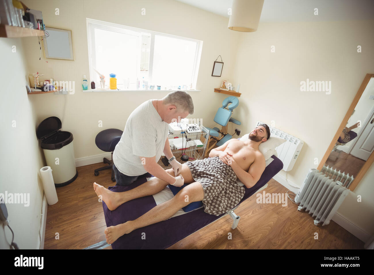 Physiotherapist performing dry needling on the knee of a patient Stock ...