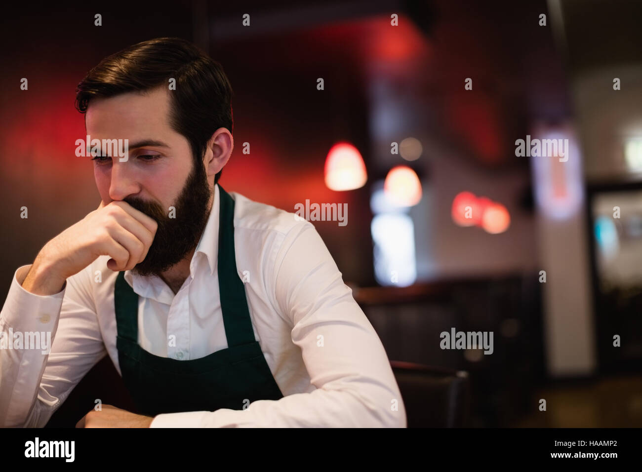 Thoughtful waiter standing near bar counter Stock Photo - Alamy