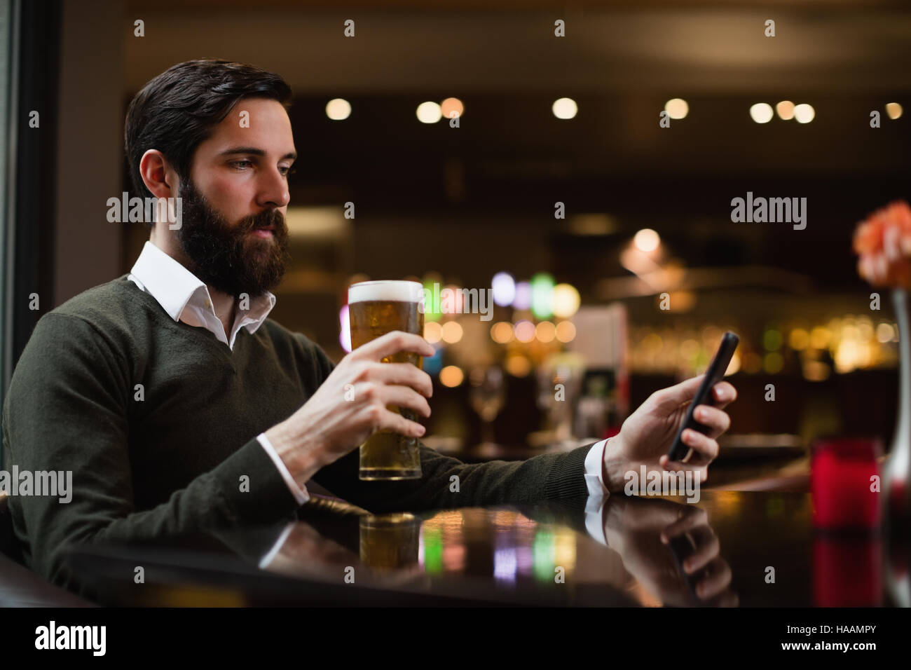 Man looking at mobile phone while having glass of beer Stock Photo - Alamy