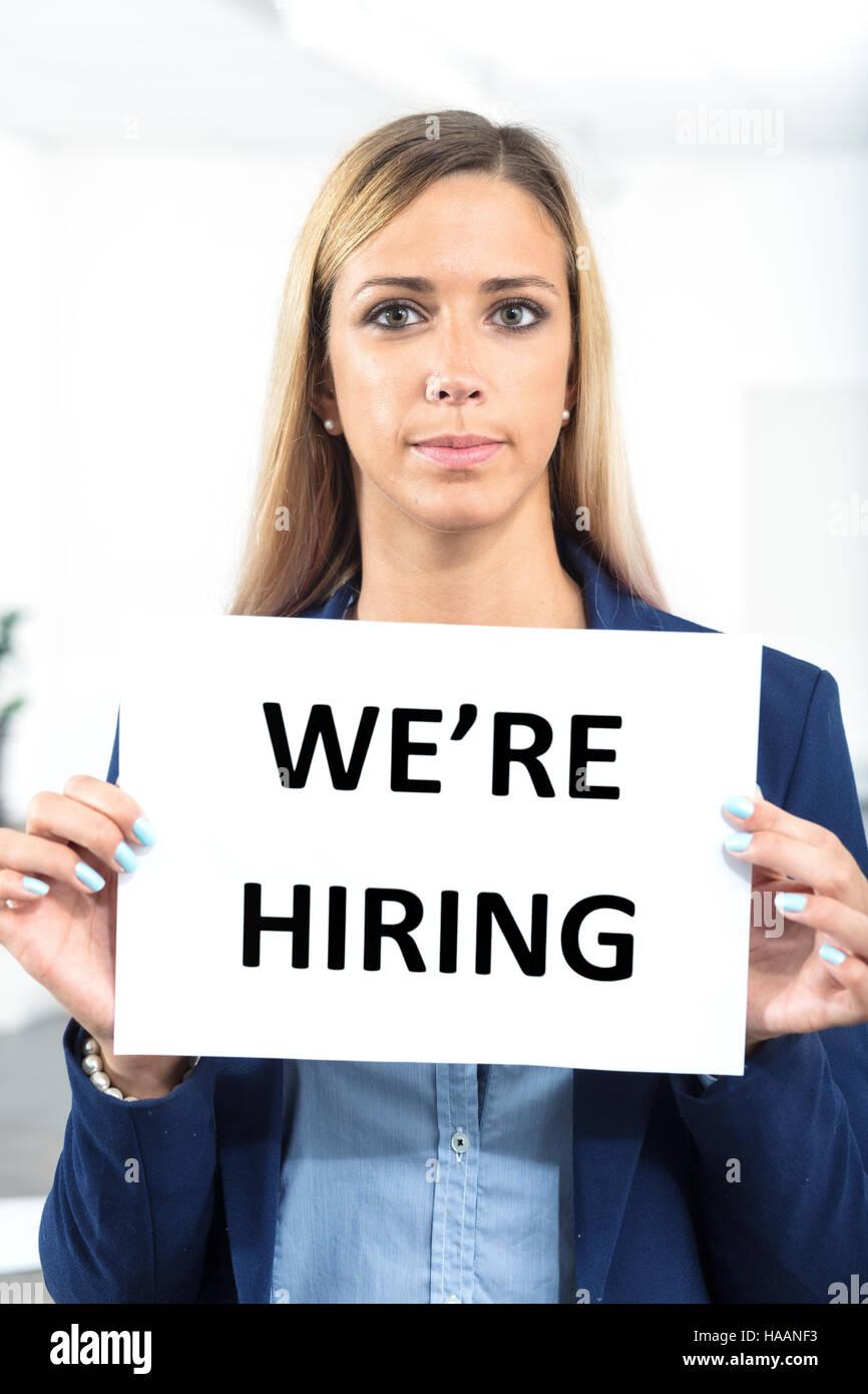 young woman holding hiring sign in a worklace bacground Stock Photo - Alamy