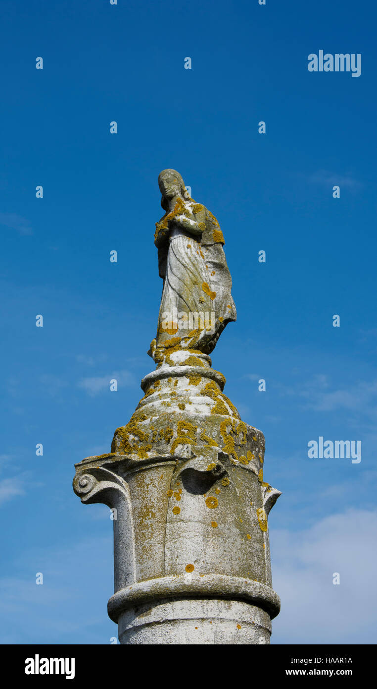 Medieval statue of a saint on an ancient column with lichen, in the ...