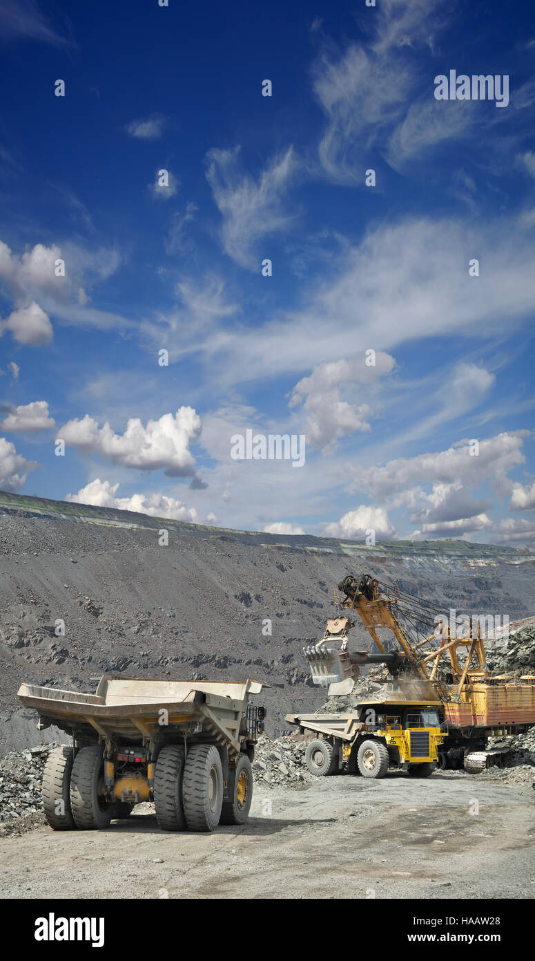 Heavy mining trucks are being loaded with iron ore on the opencast ...