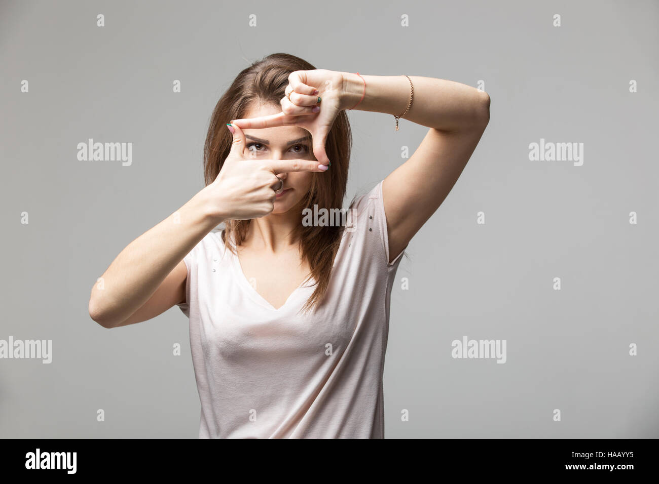 Closeup of young beautiful brunette woman making frame with her fingers ...